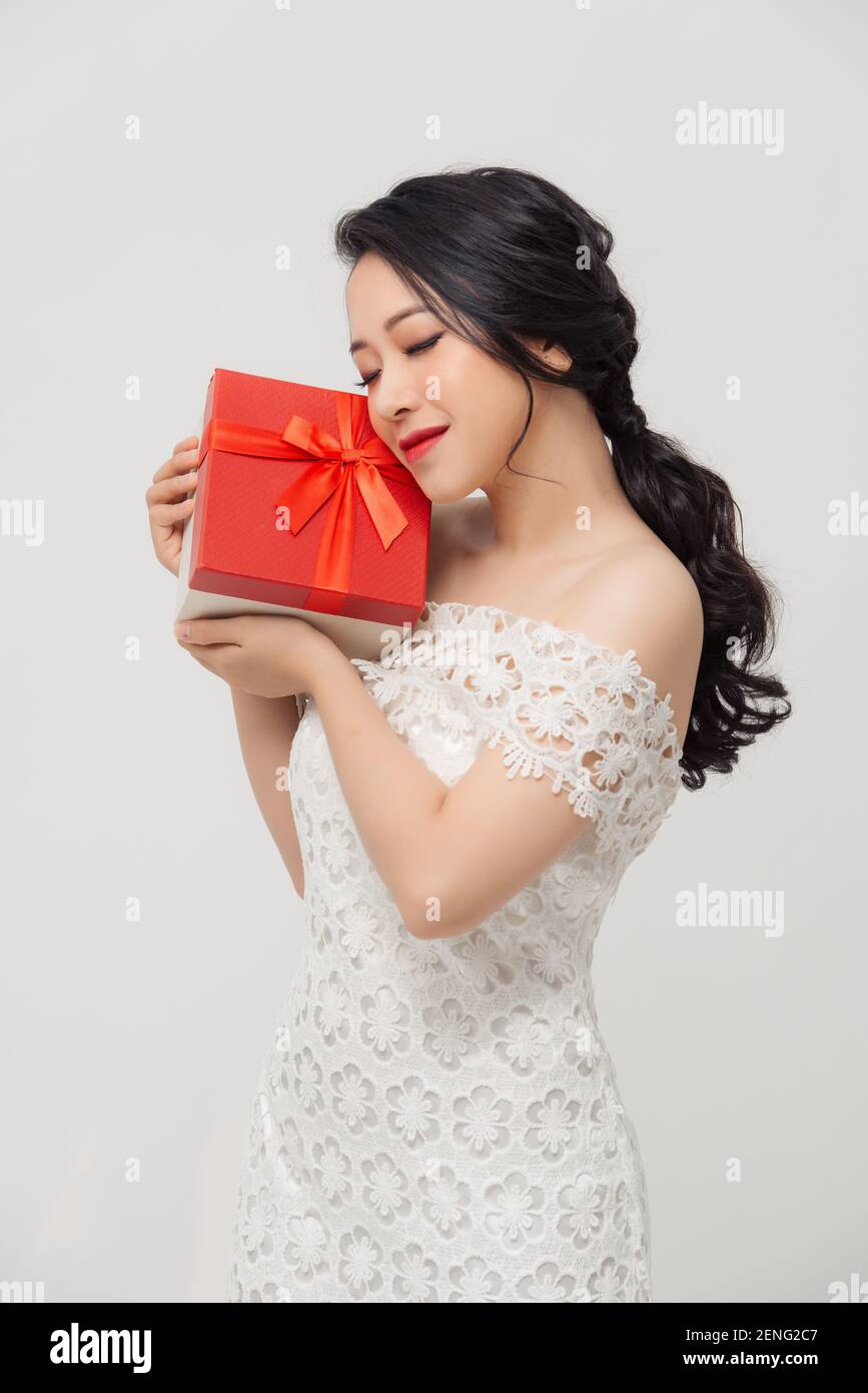 Happy young elegant Asian woman holding special gift box and wearing ...