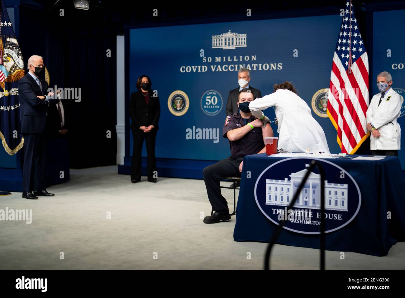 President Joe Biden looks on as a nurse gives a vaccine to Corey ...