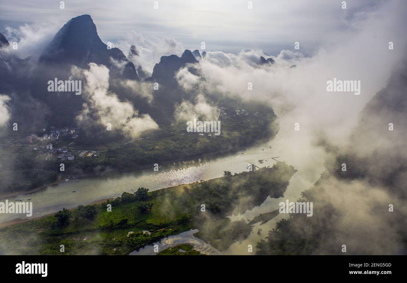 The mountains and hills are surrounded by mist and cloud along the Li ...