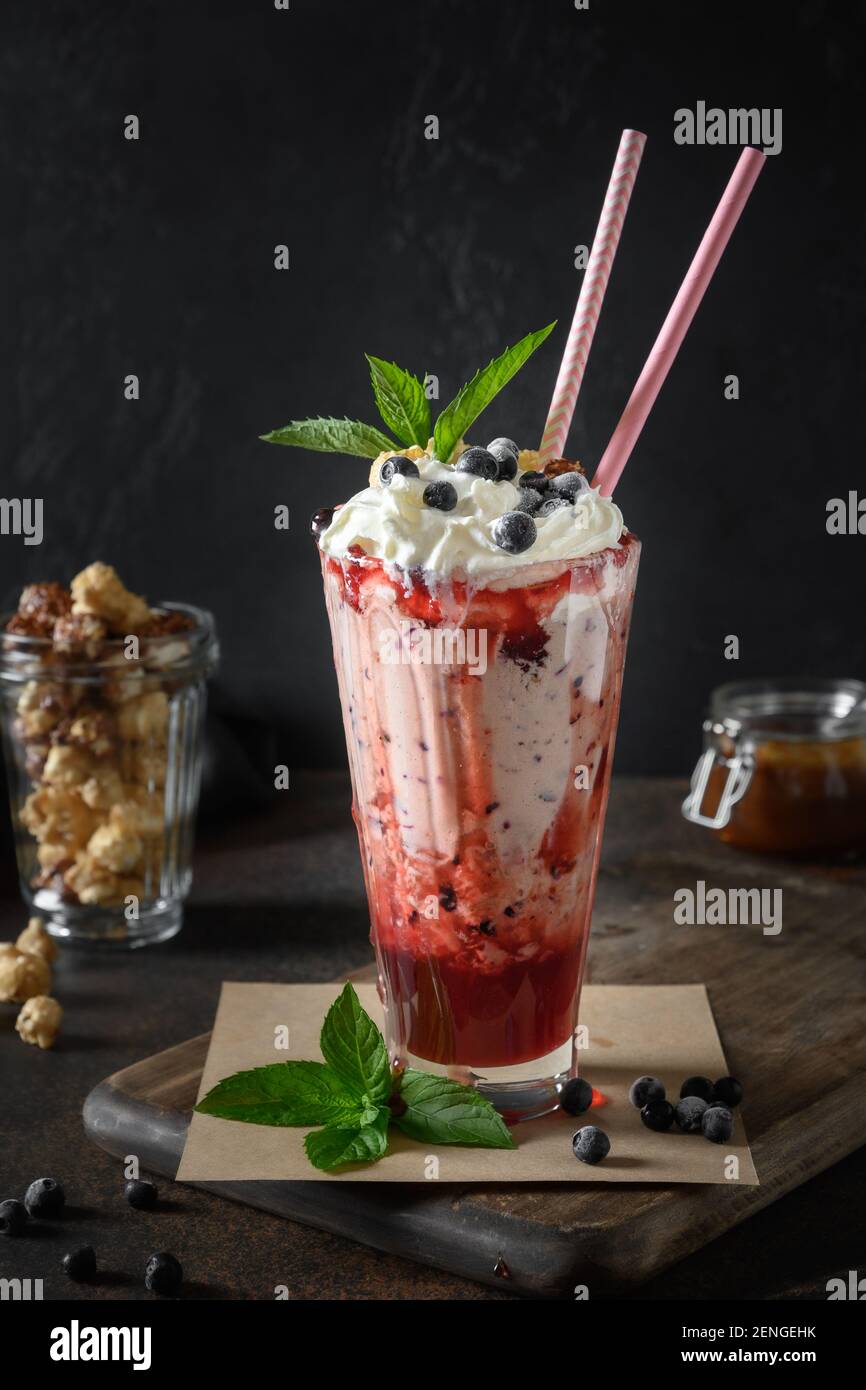 Delicious blueberrie milkshake with whipped cream, dripping jam on dark ...