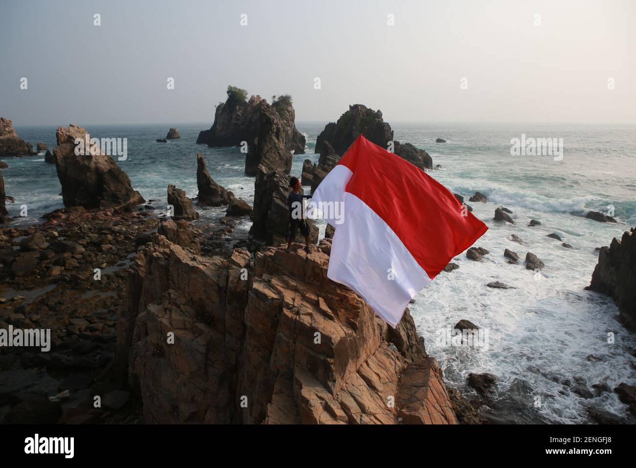 An Indonesian man seen carrying the Indonesian flag, on the rock of ...