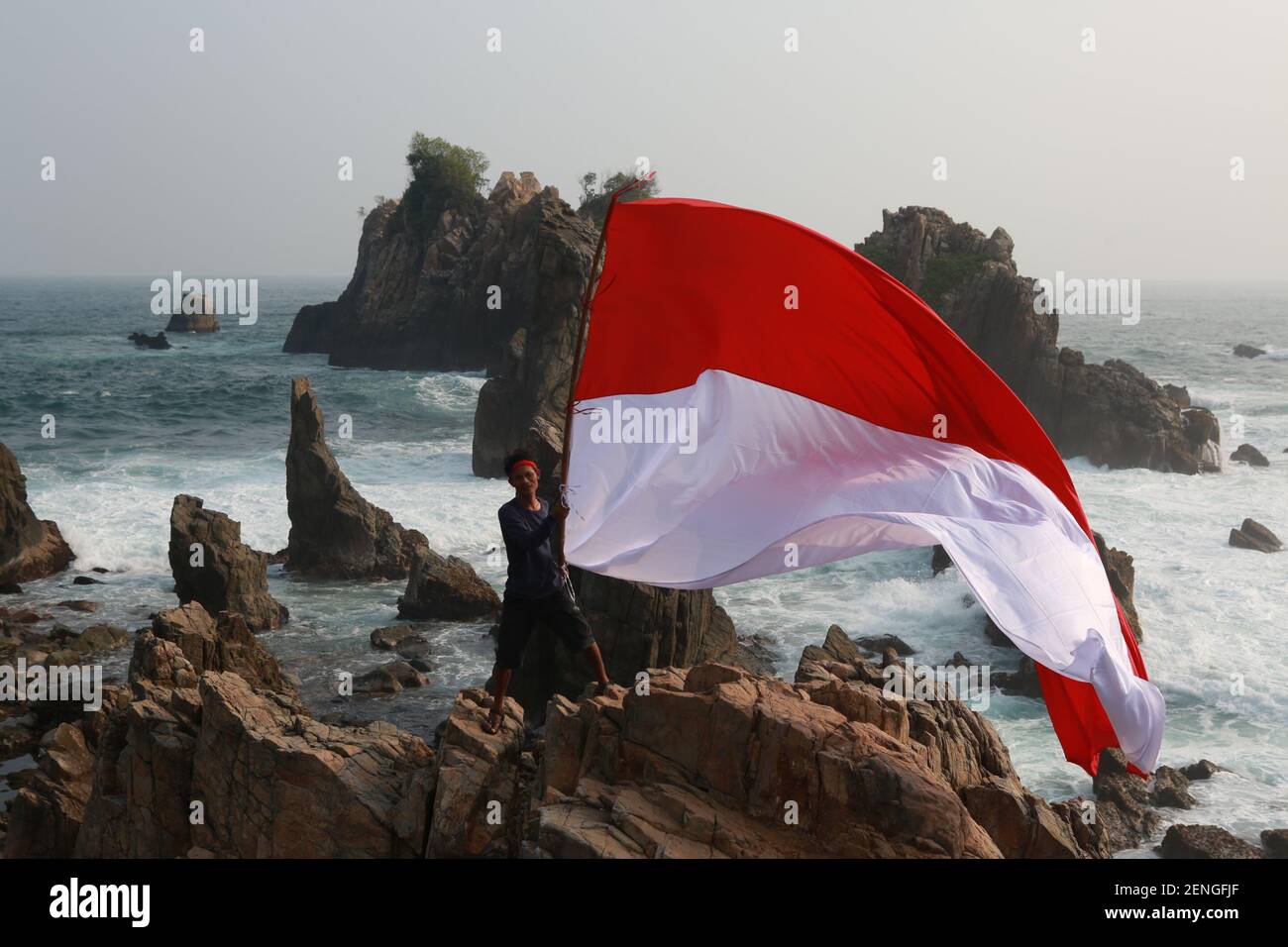 An Indonesian man seen carrying the Indonesian flag, on the rock of ...
