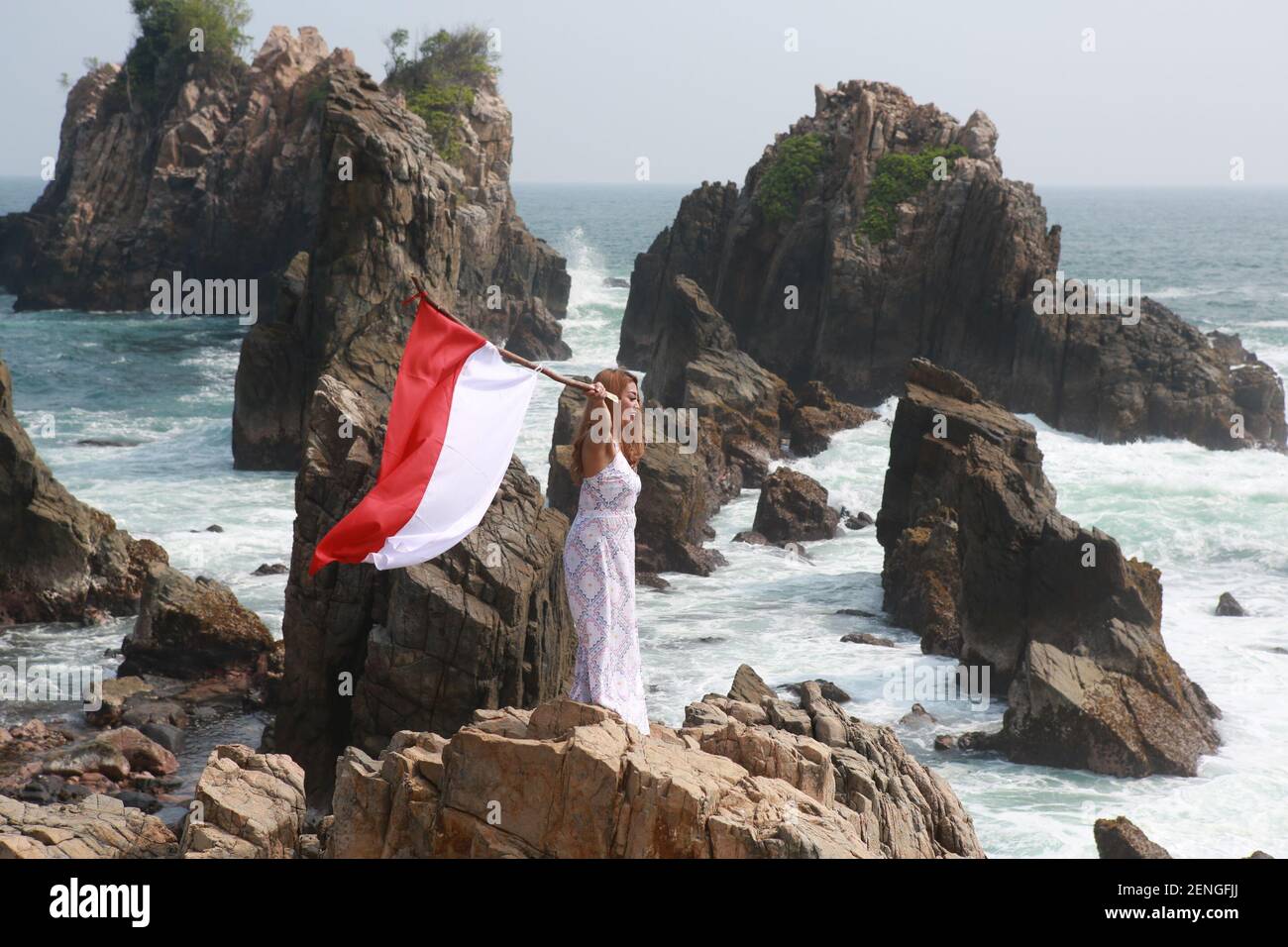 An Indonesian woman seen carrying the Indonesian flag, on the rock of ...