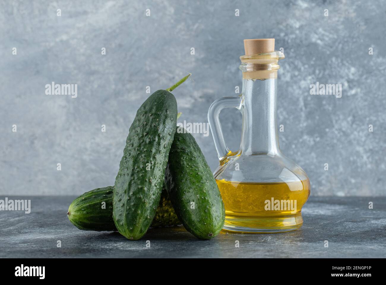 Pile of cucumber with bottle of oil over grey background Stock Photo ...