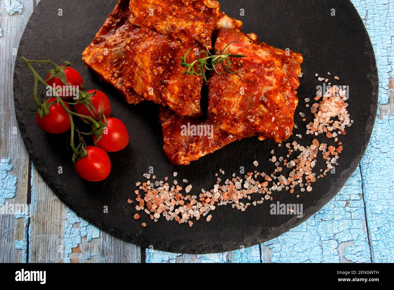 Raw marinated pork ribs on black stone plate ready for cooking. Raw bbq ...
