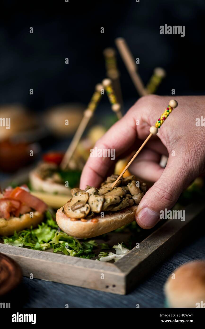 closeup of a young man taking a vegan spanish pincho from a tray with ...