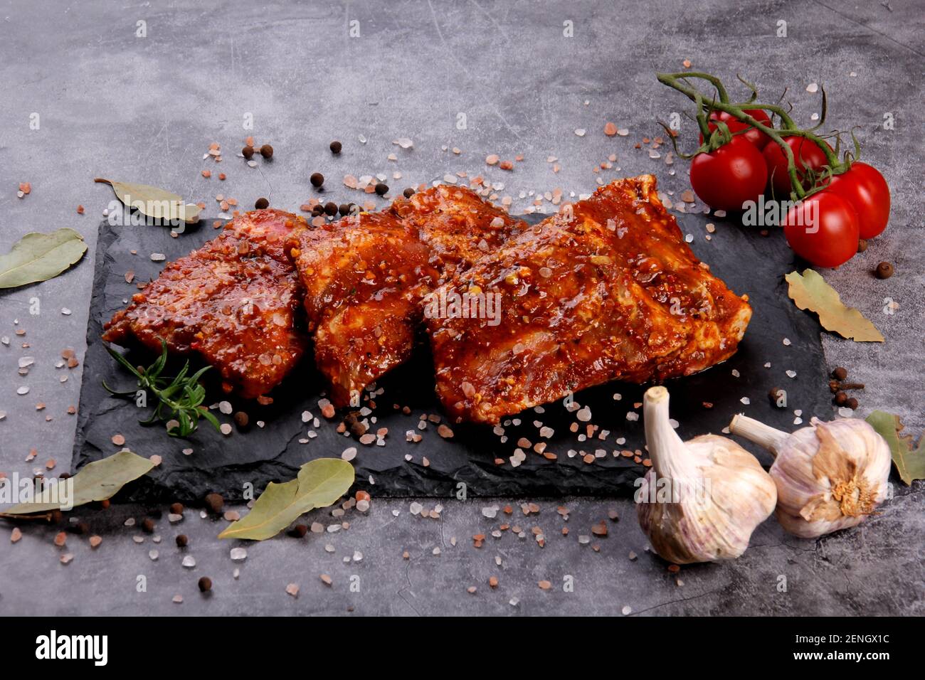 Raw marinated pork ribs on black stone plate ready for cooking. Raw bbq ...