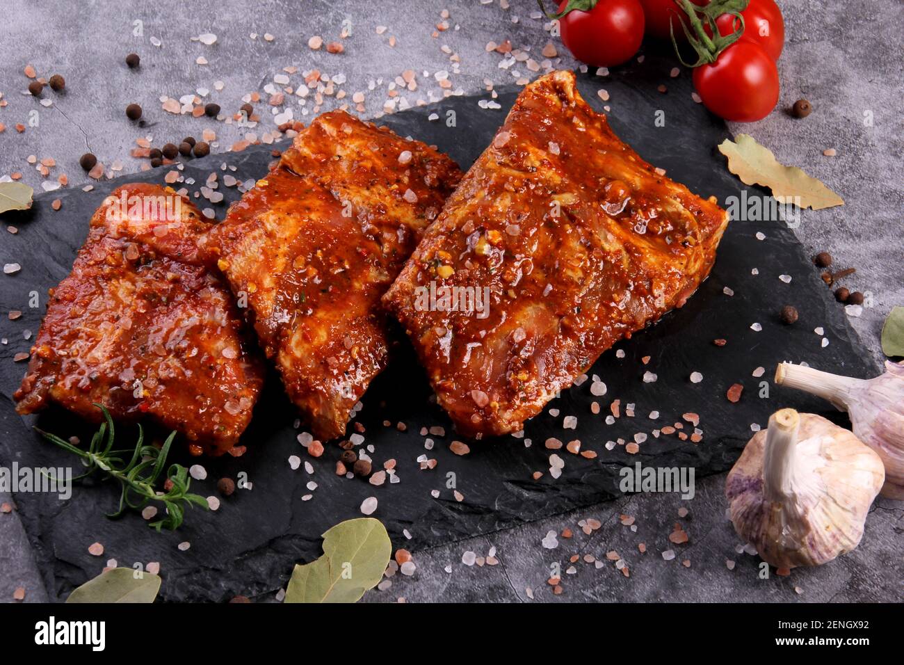 Raw marinated pork ribs on black stone plate ready for cooking. Raw bbq ...