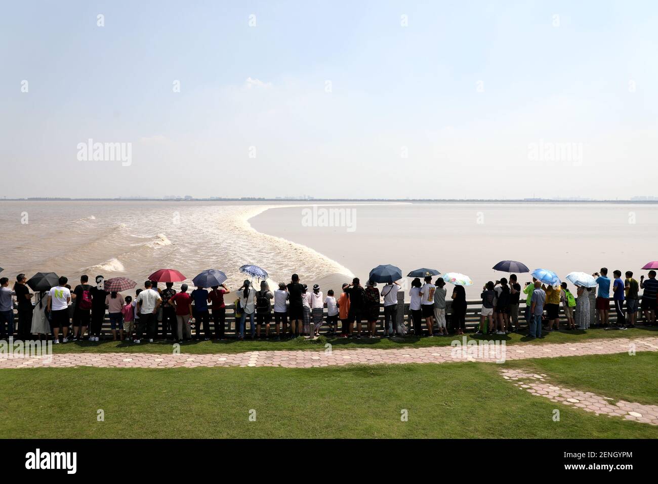 Waves from a tidal bore of the Qiantang River gush over the river bank ...