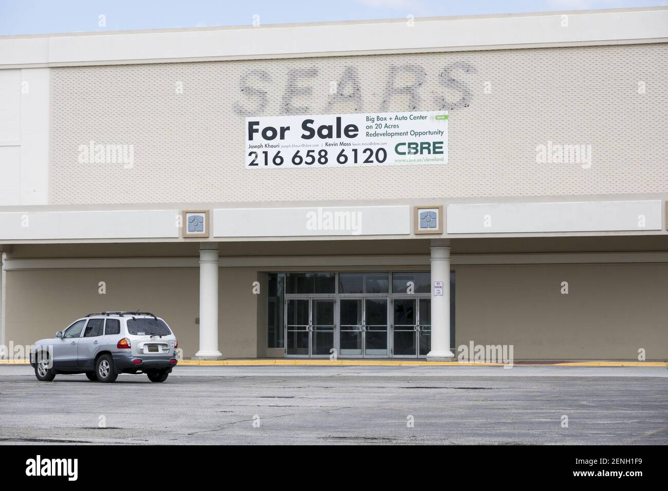 A faded outline of a logo sign outside of a closed and abandoned Sears ...