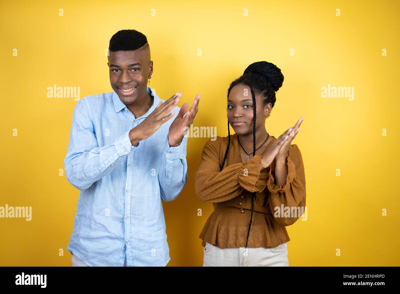 Young african american couple standing over yellow background clapping ...