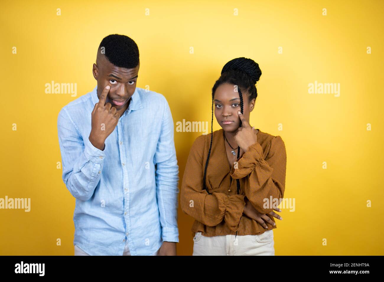 Young african american couple standing over yellow background Pointing ...