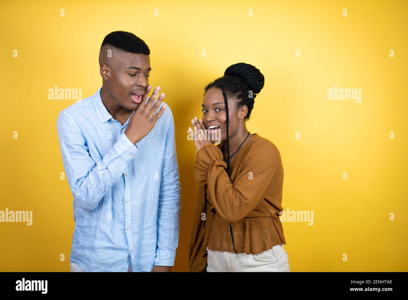 Young african american couple standing over yellow background hand on ...