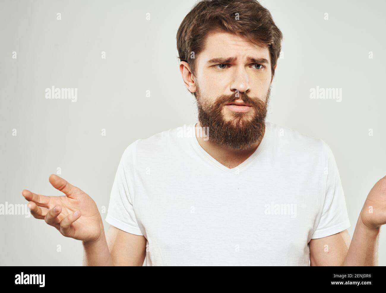 The man looks ahead in a puzzled way on a light background of emotions ...