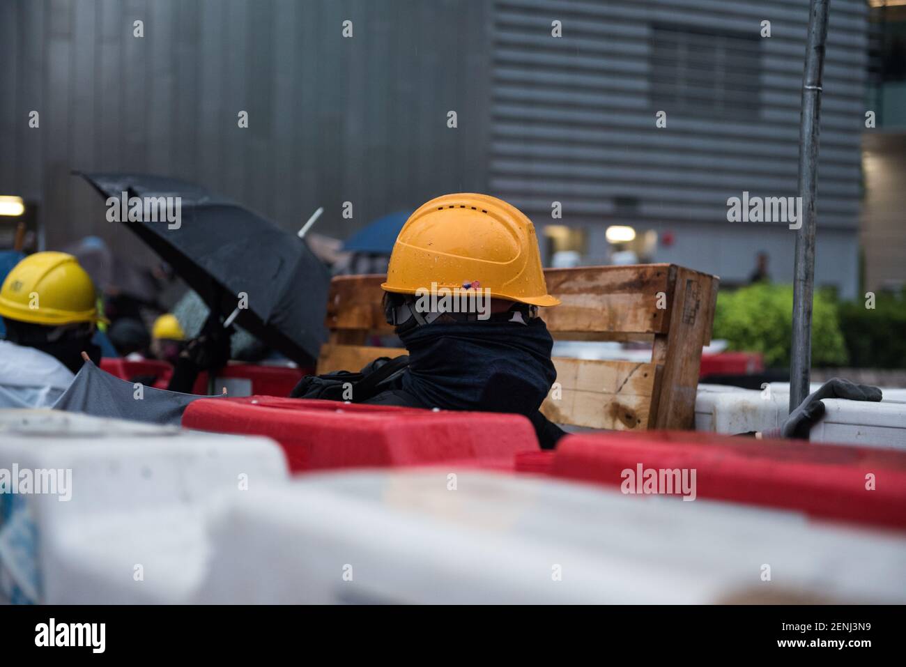 A protester takes cover behind a plastic and wooden barricades during ...