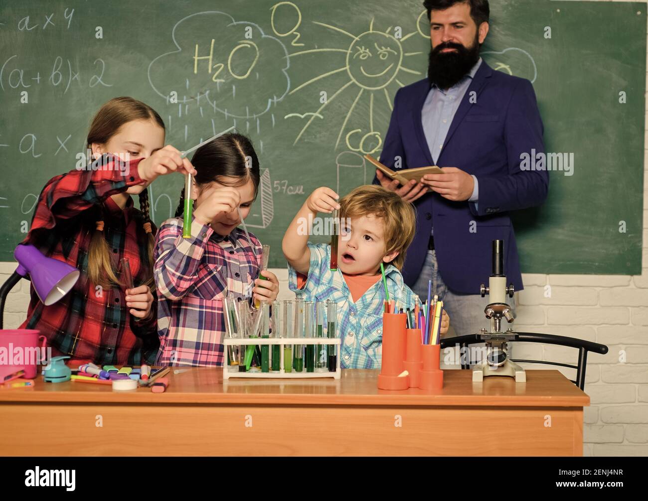 Topic of our club. Teacher and pupils test tubes in classroom ...