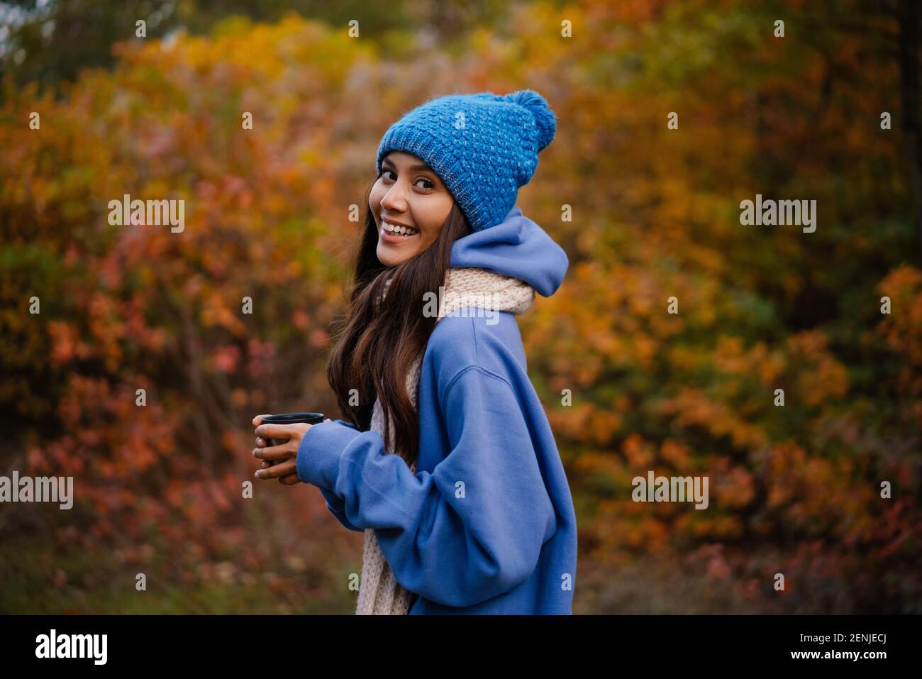 Nice brunette happy woman in knit hat drinking tea while strolling in autumn forest Stock Photo ...