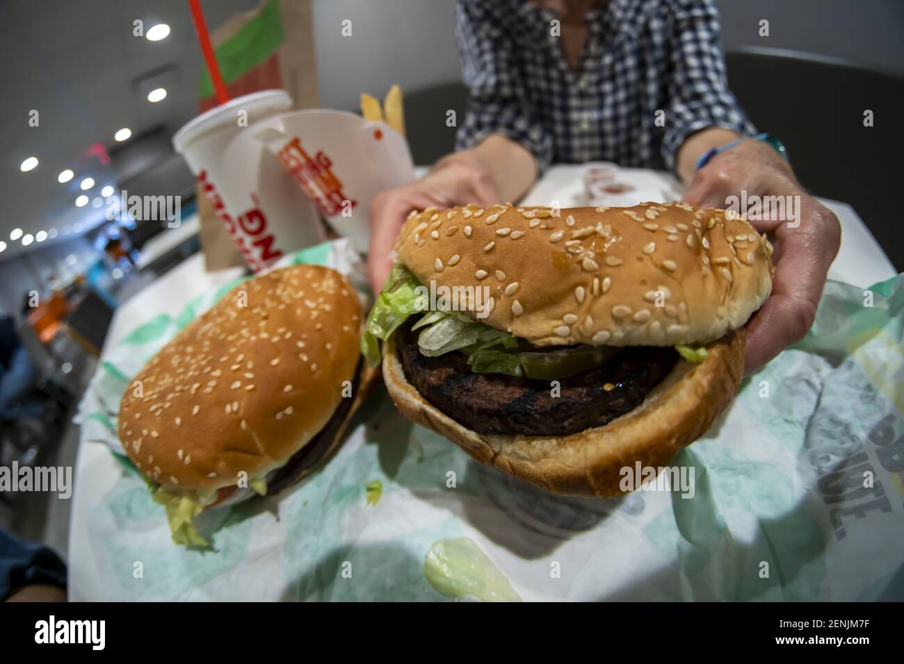 A diner enjoys a Burger King Impossible Whopper, a meatless ground beef ...