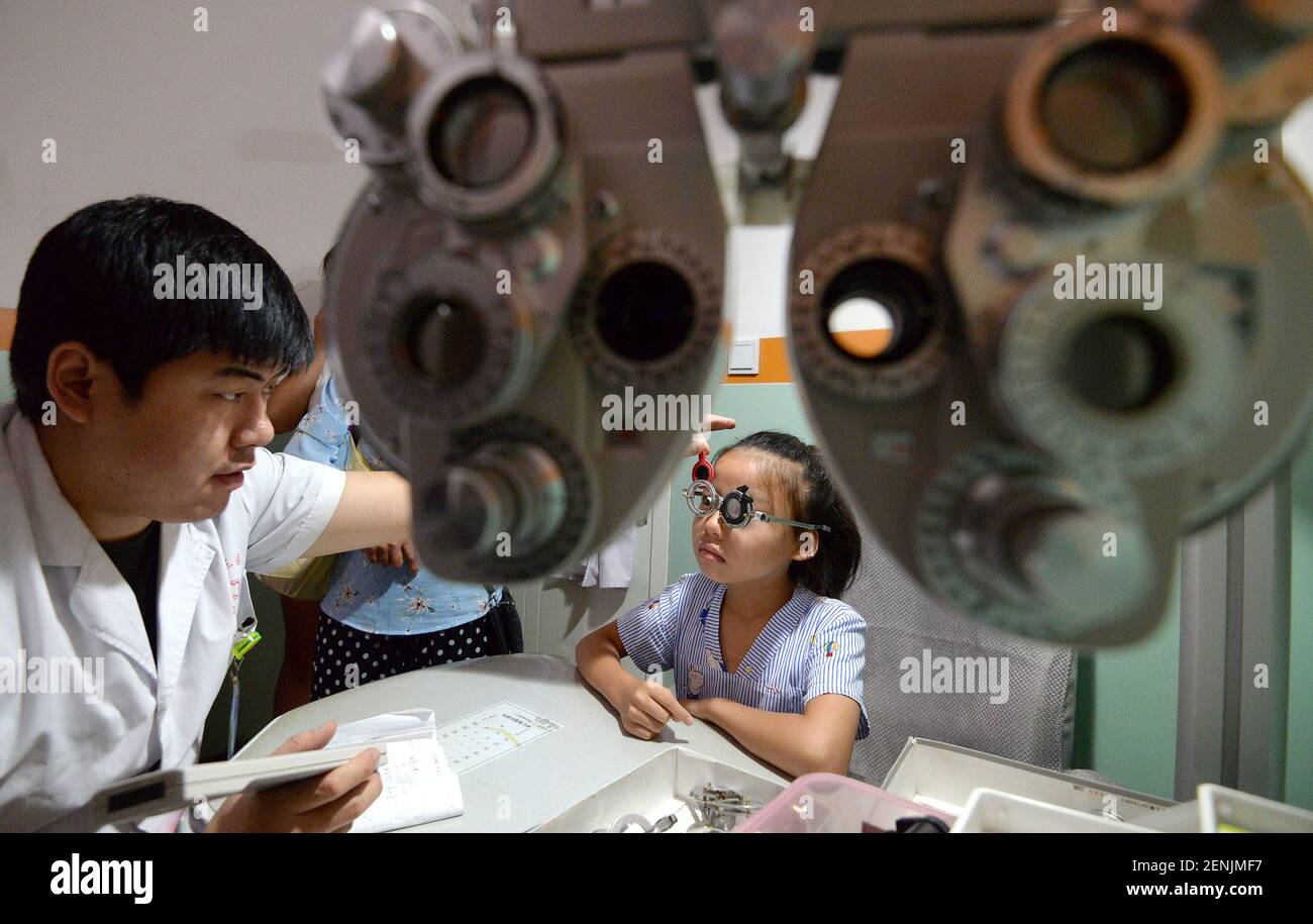 A Chinese doctor examines the eyesight of a young myopic kid at an ...