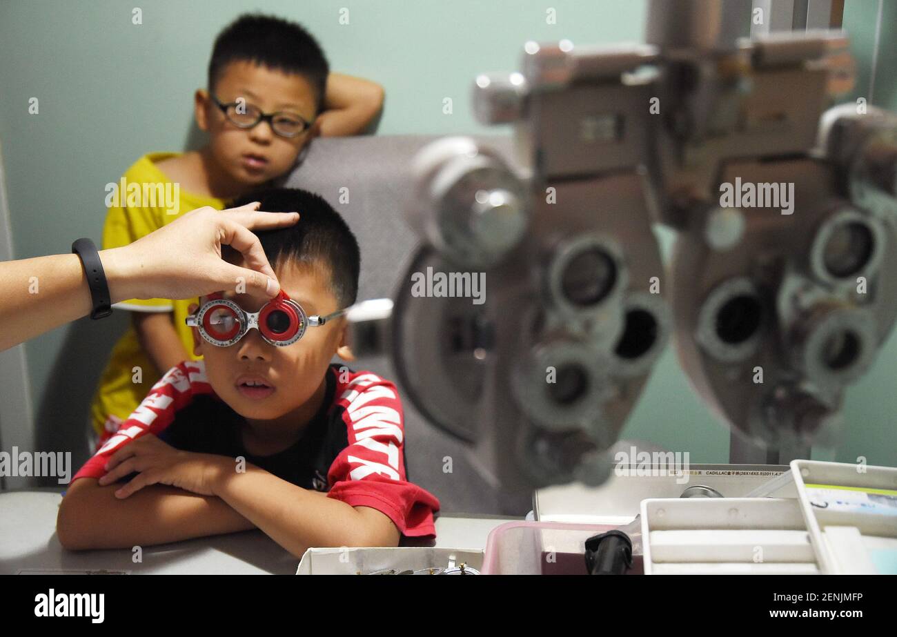 A Chinese doctor examines the eyesight of a young myopic kid at an ...