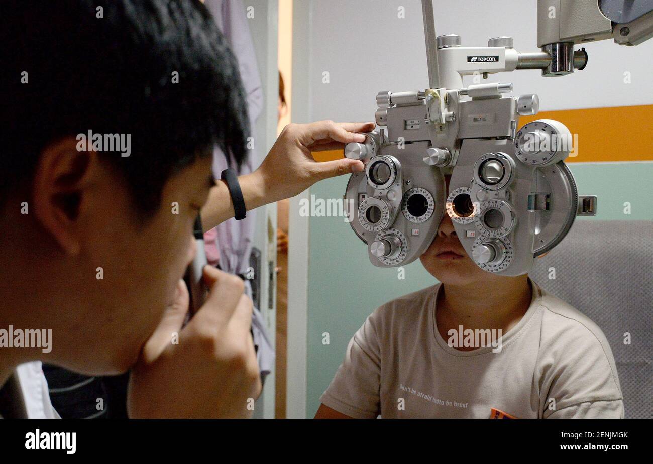 A Chinese doctor examines the eyesight of a young myopic kid at an ...