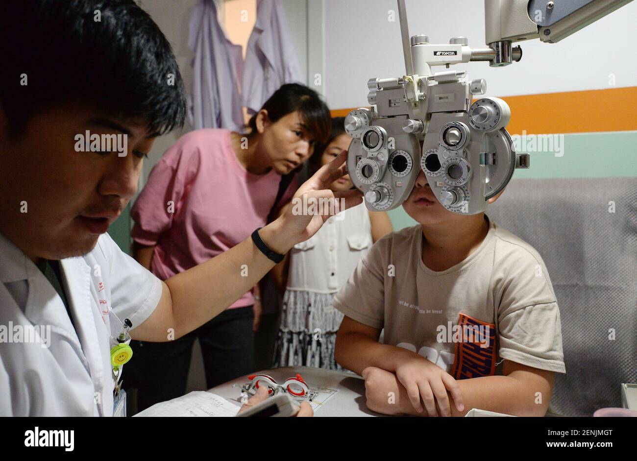 A Chinese doctor examines the eyesight of a young myopic kid at an ...