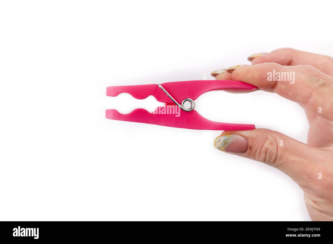 female hand holding a clothespin of pink color isolated on white ...