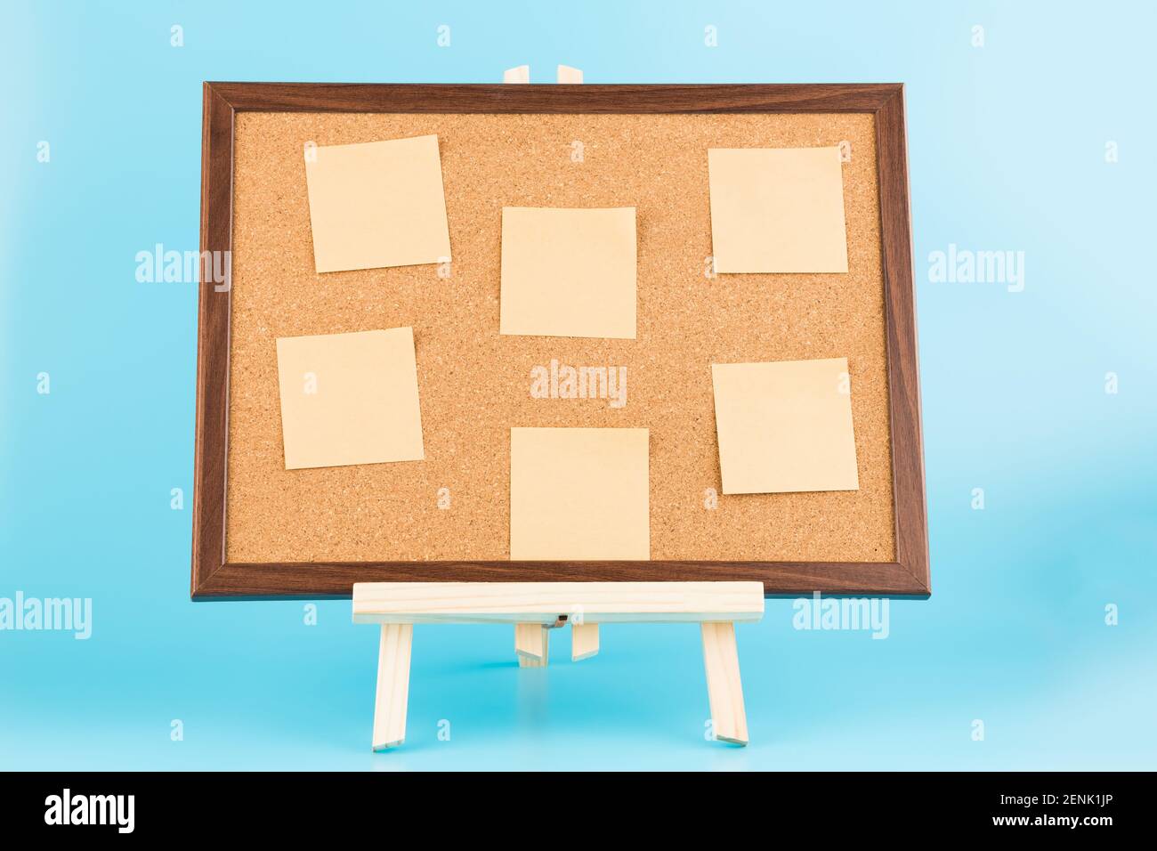 Wooden easel with cork boardand paper stickers on blue background Stock ...