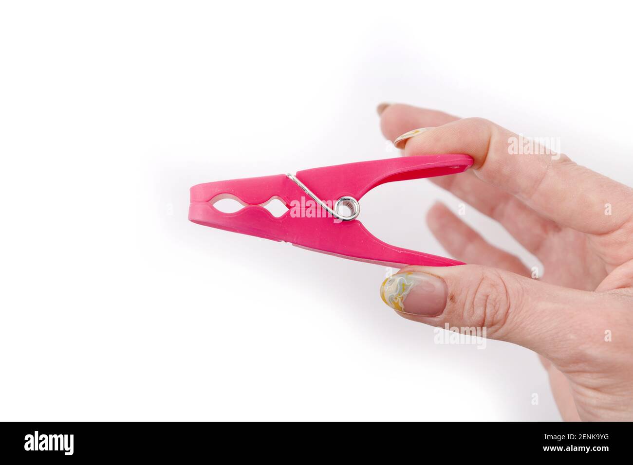 female hand holding a clothespin of pink color isolated on white ...