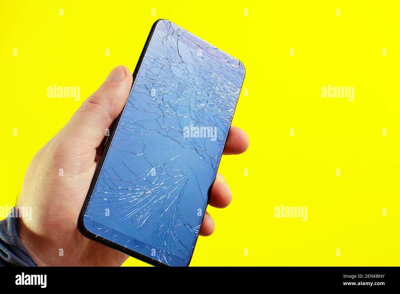 A broken touch phone with a cracked screen in your hand on a yellow ...