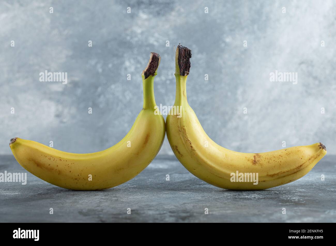 Two fresh banana side by side over grey background Stock Photo - Alamy