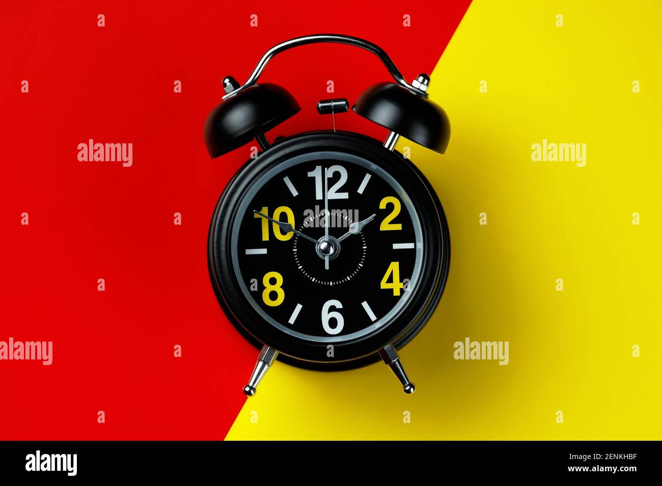 Black round metal alarm clock on legs on a bright composite background ...