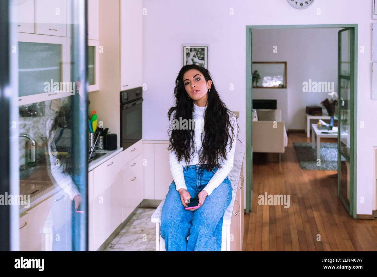 Young woman sitting on kitchen counter Stock Photo - Alamy