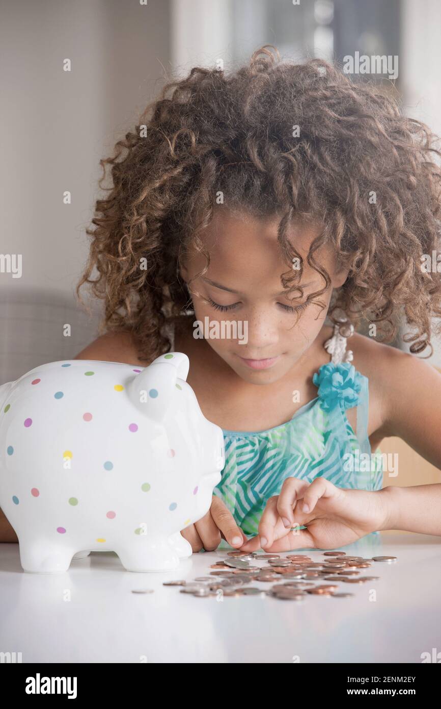 Girl with piggy bank counting coins Stock Photo - Alamy