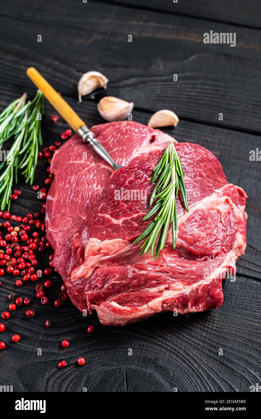 Fresh Raw Chuck eye roll beef steak on butcher table. Black wooden ...