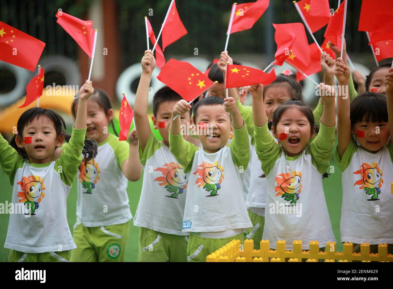 Young Chinese kids wave Chinese national flags behind a model of the ...