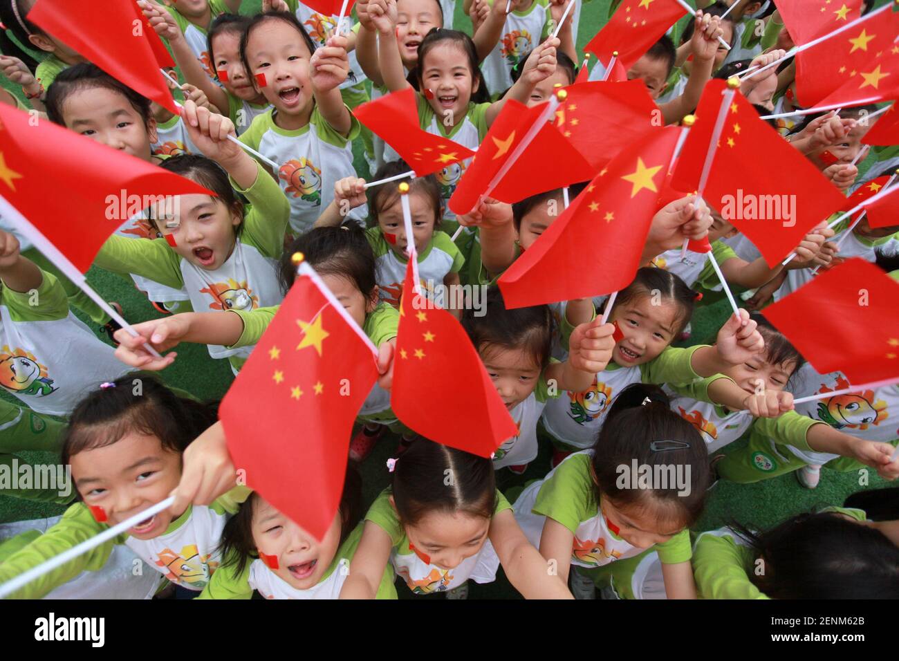 Young Chinese kids wave Chinese national flags behind a model of the ...