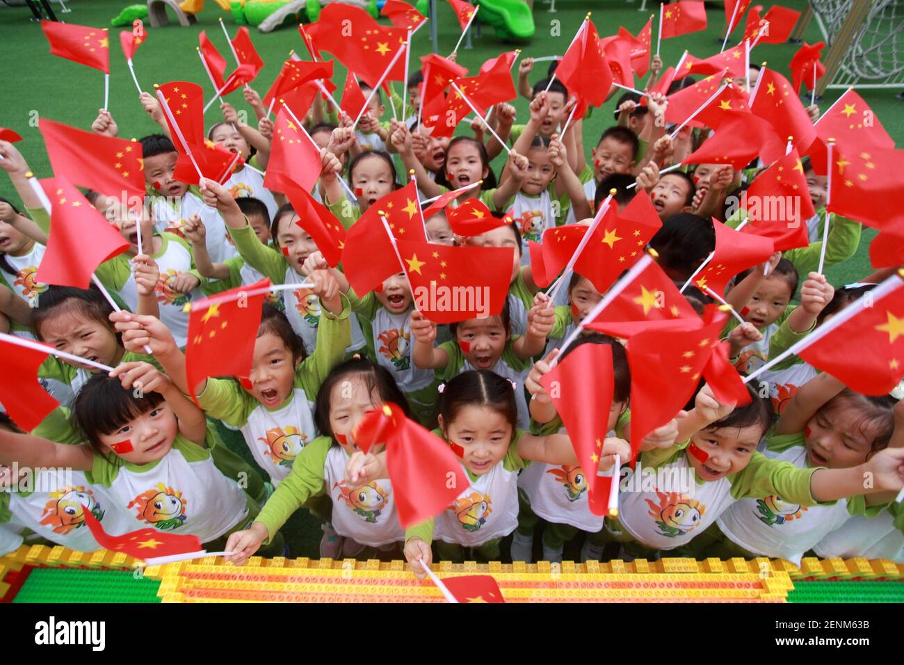 Young Chinese kids wave Chinese national flags behind a model of the ...