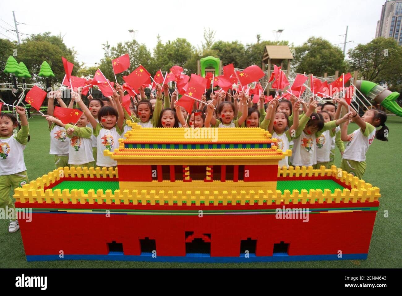 Young Chinese kids wave Chinese national flags behind a model of the ...