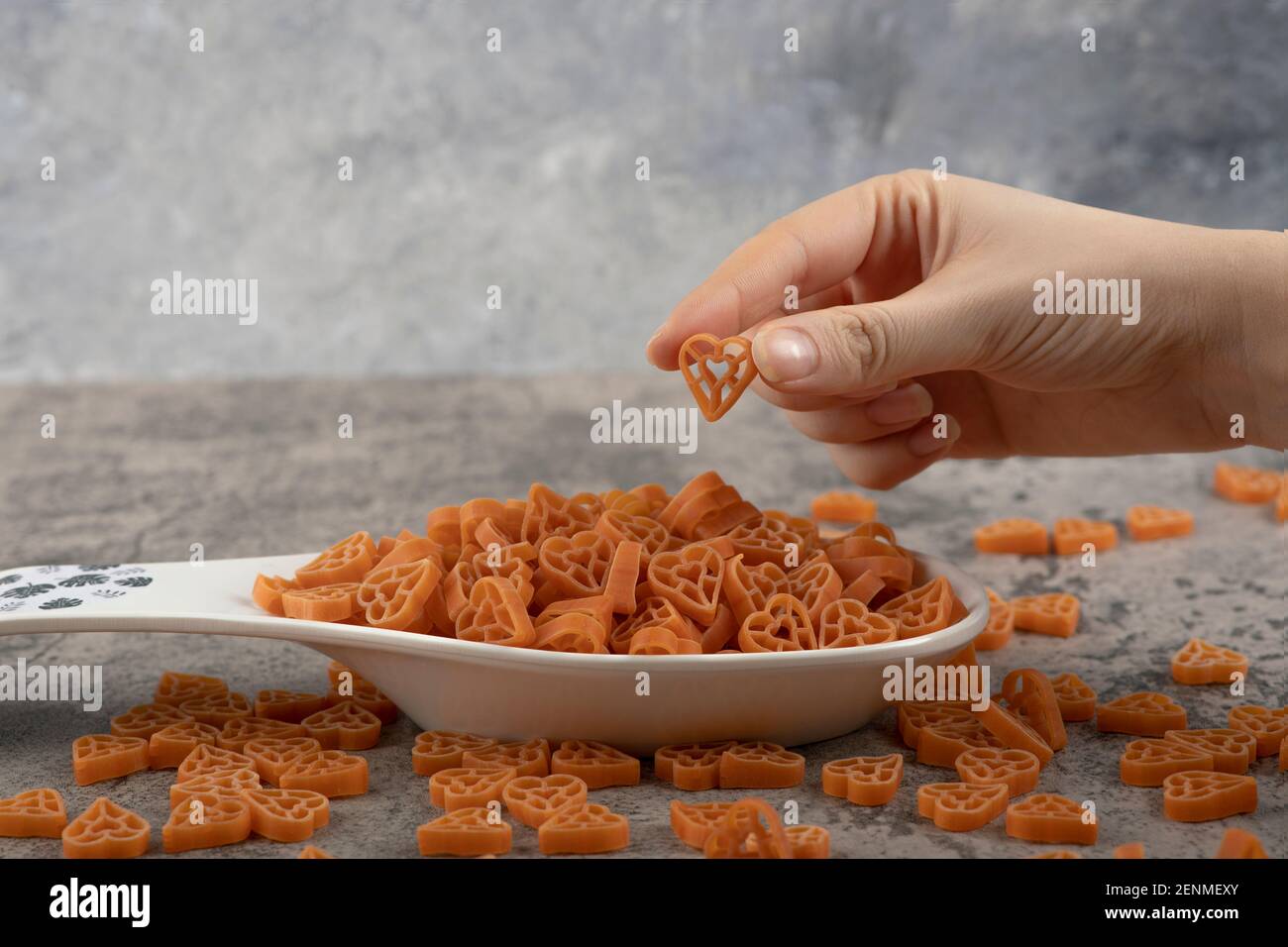 Female hand picking raw macaroni from plate on marble background Stock ...