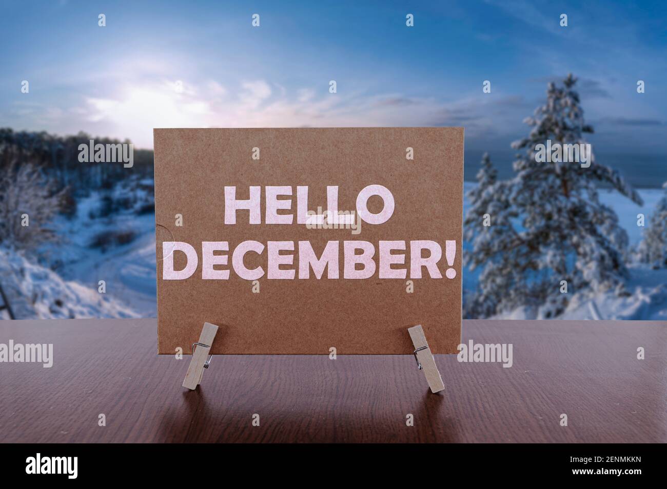 Hello December text on card on the table with sunny winter landscape ...