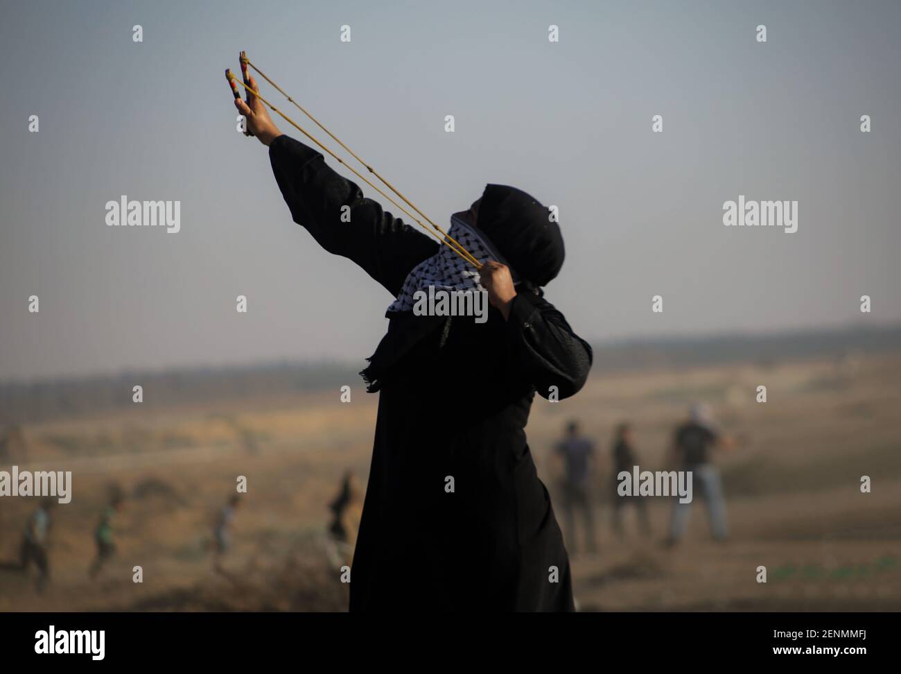 A Palestinian demonstrator uses a slingshot to throws stones during an ...