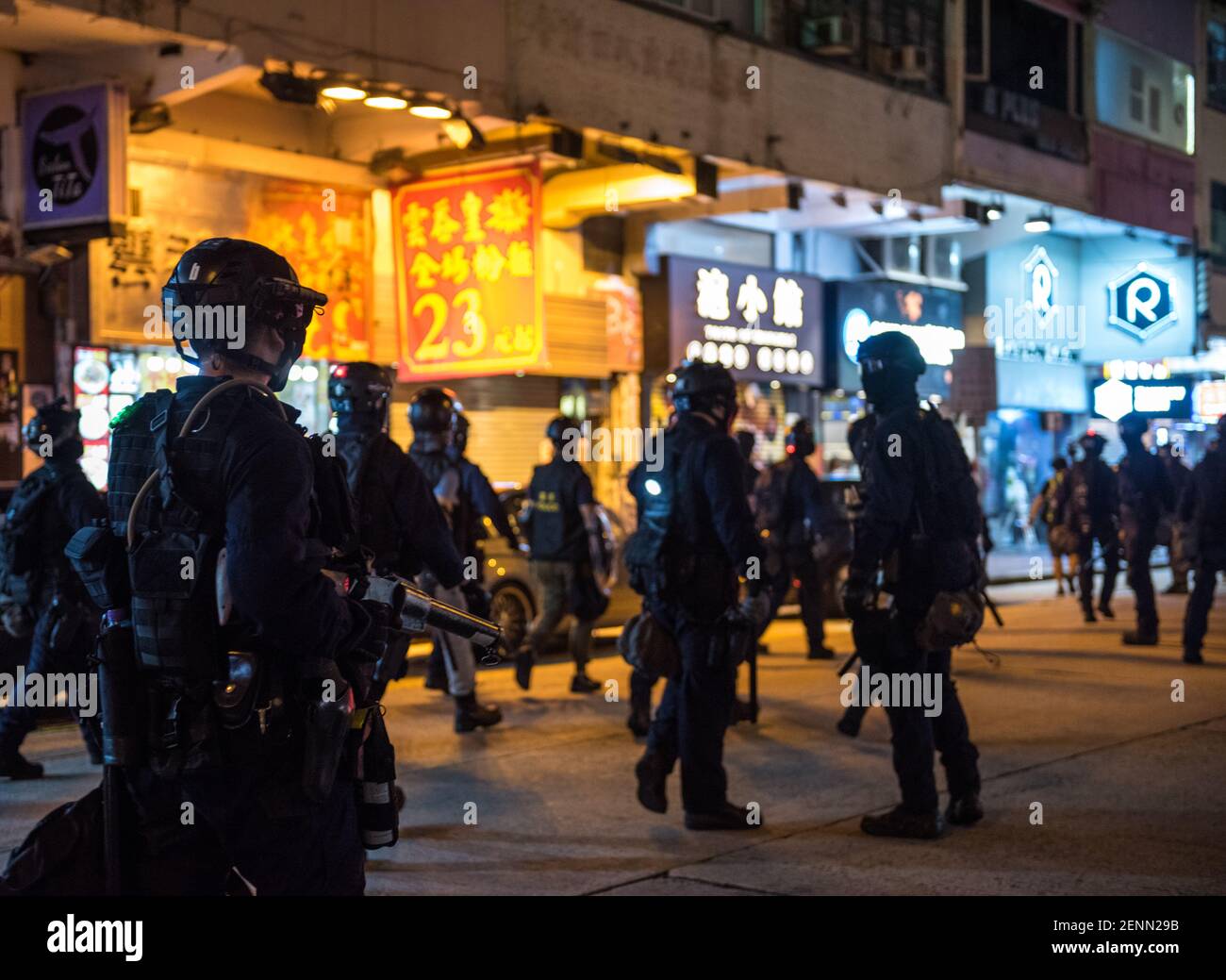 Riot police officers walk down the street after chasing off protesters ...