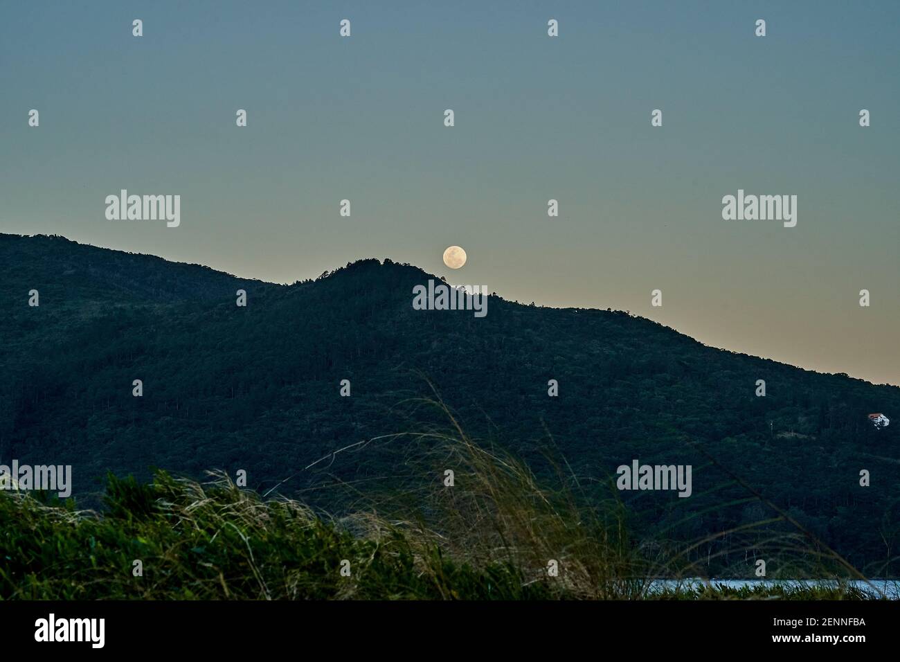 Full moon rising over the beautiful landscape of a mountain ridge with ...