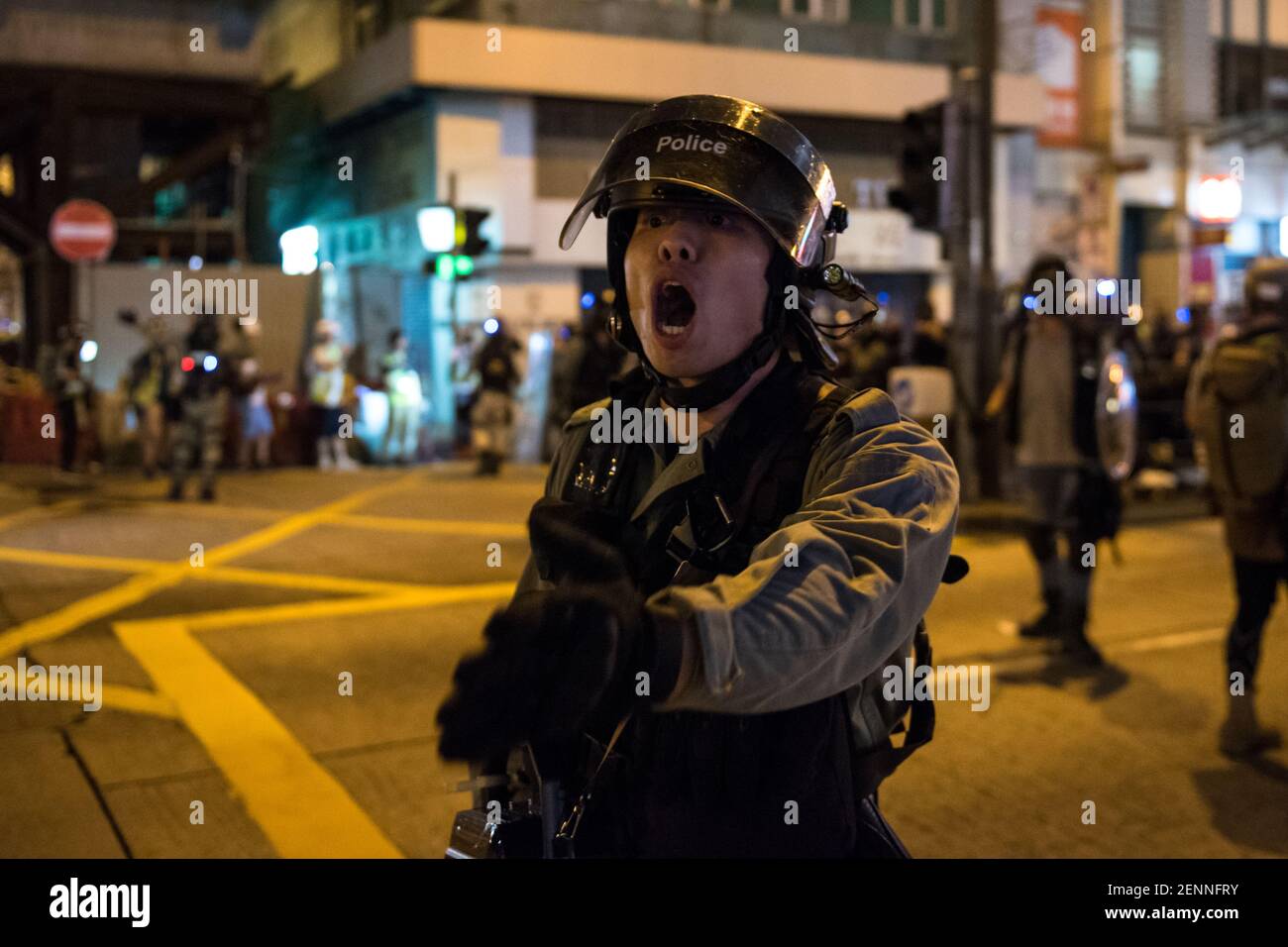 A riot police officer yells at journalists to back away from the scene ...