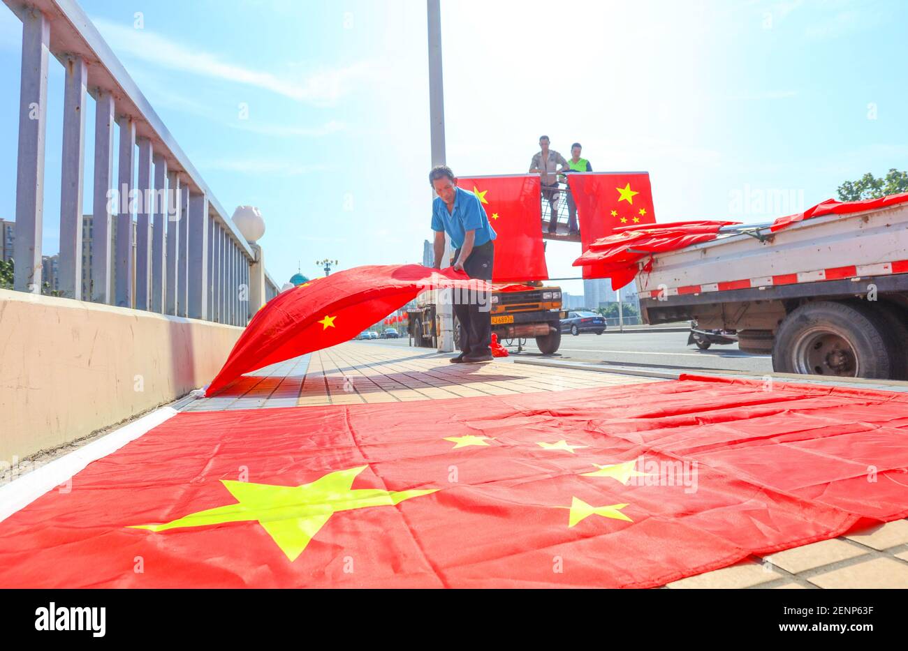 Workers hang national flags in streets to celebrate the 70th National ...