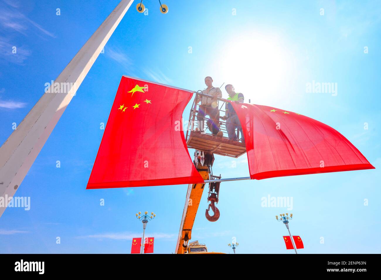 Workers hang national flags in streets to celebrate the 70th National ...