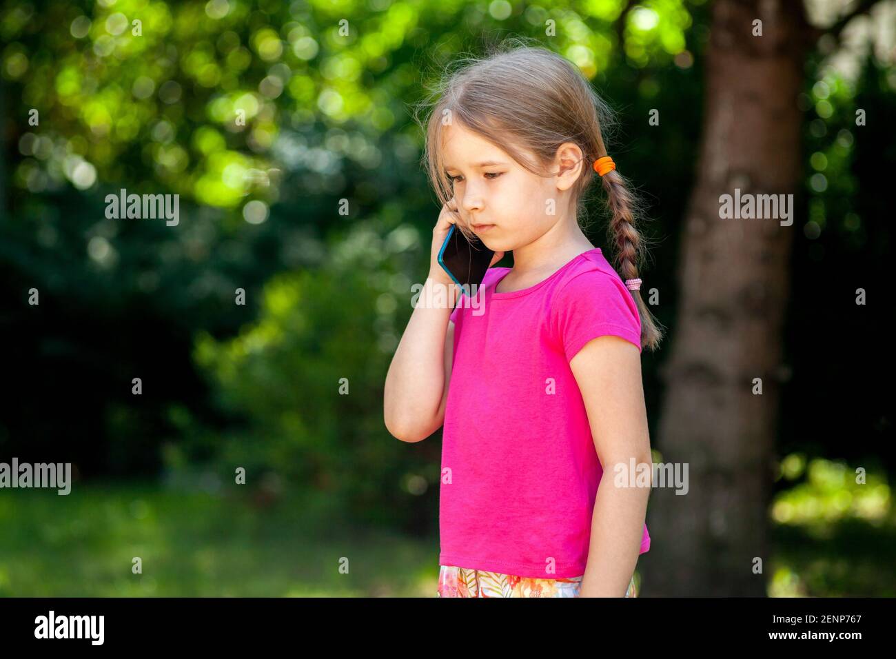 Sad lone little school age girl, child talking on the phone, smartphone ...