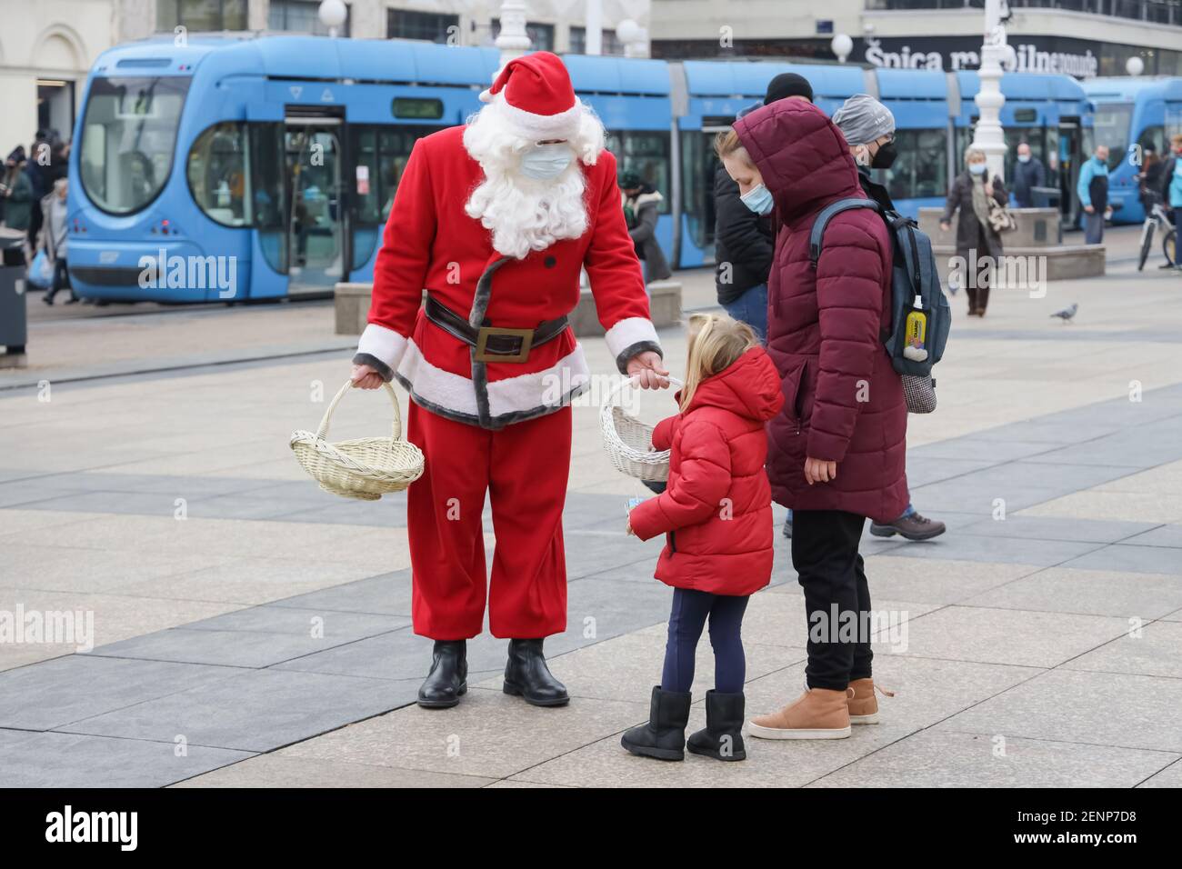 Santa Claus gives candies to people and wears a medicine mask on the ...