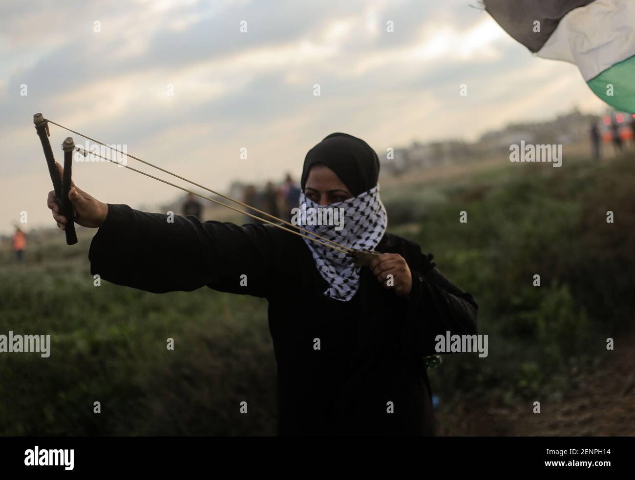A Palestinian demonstrator uses a slingshot to throw stones during an ...